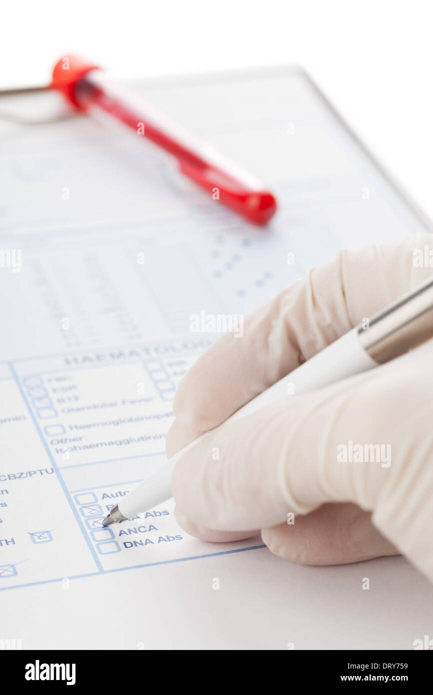 Doctor filling out blood test form with blood sample vial in the ...