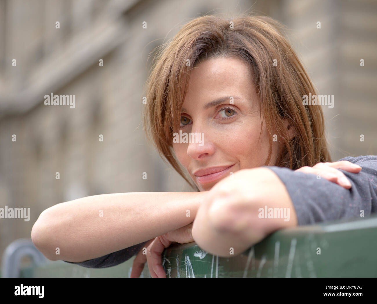 Woman leaning against railing outdoors, portrait Stock Photo - Alamy