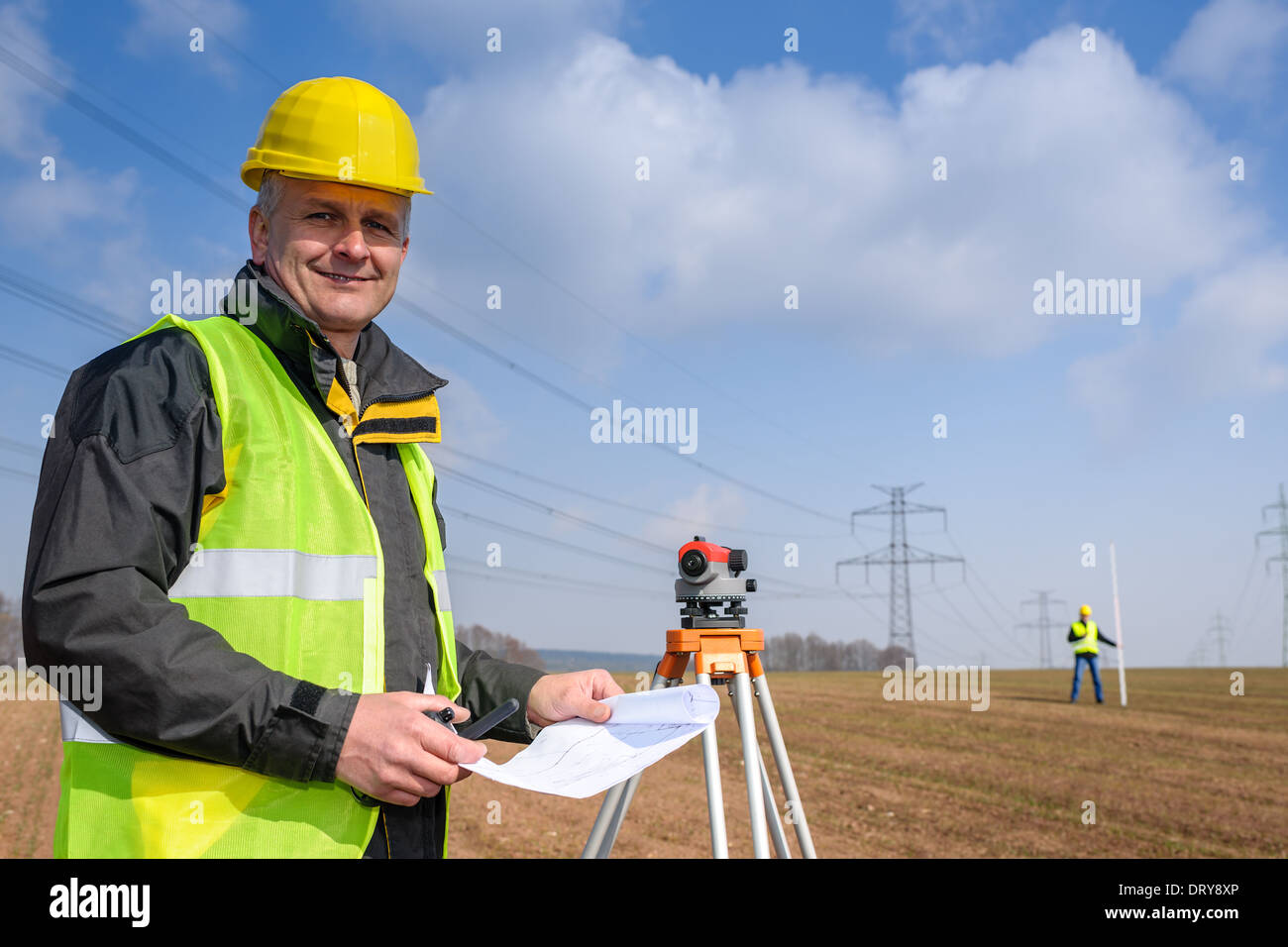 Geodesist wear reflective vest measure land Stock Photo - Alamy
