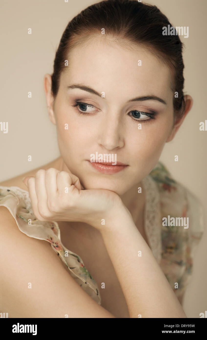 Woman with hand under chin, wearing ruffly dress, hair in bun, portrait ...