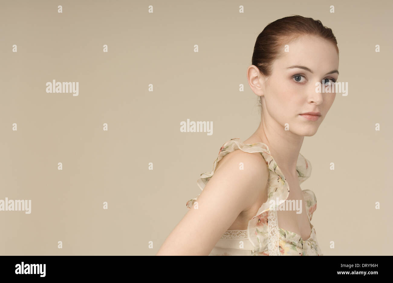 Woman wearing ruffly dress, hair in bun, looking at camera, portrait ...