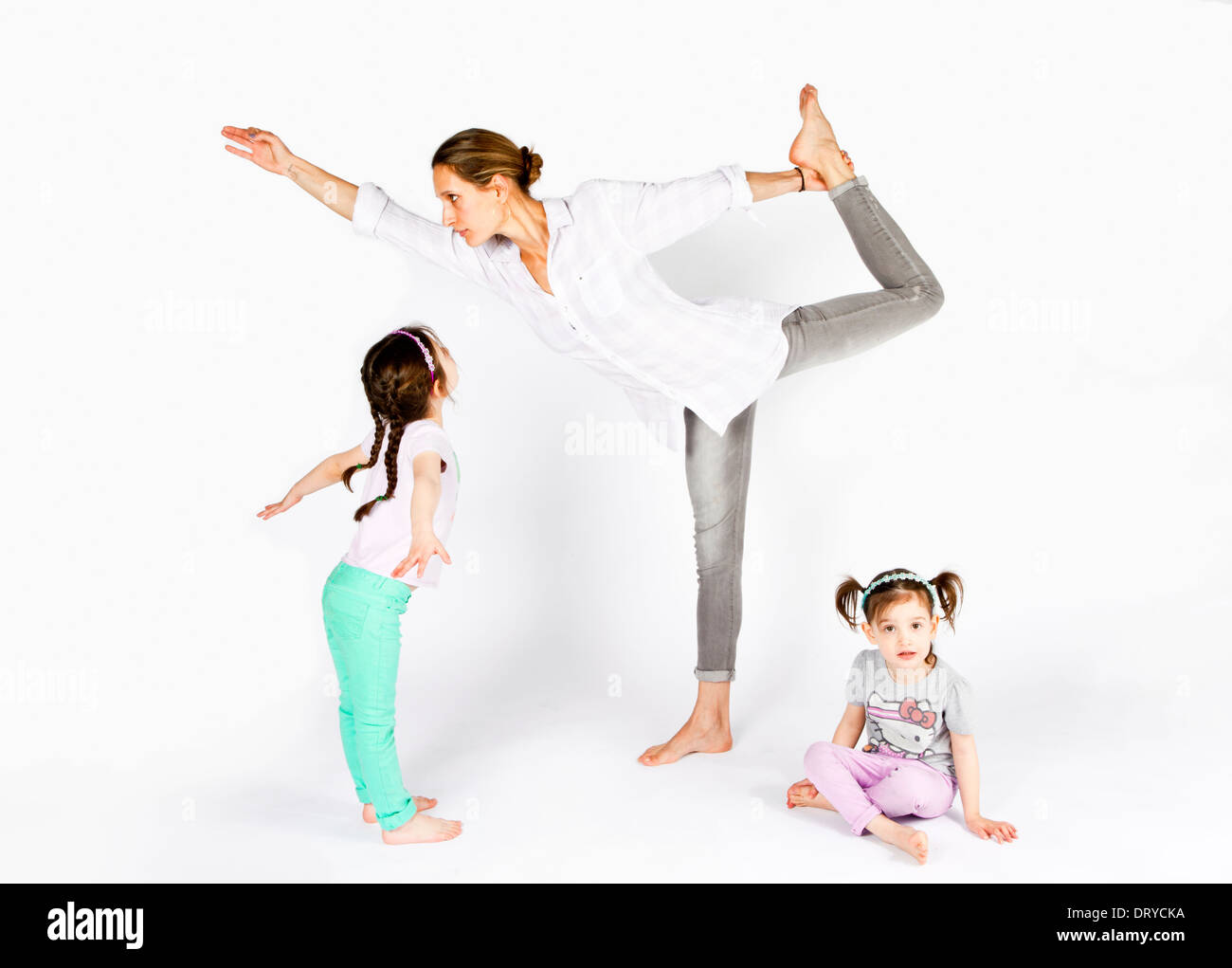 Mother doing yoga dancer pose with her two daughters (2-5 Stock Photo ...