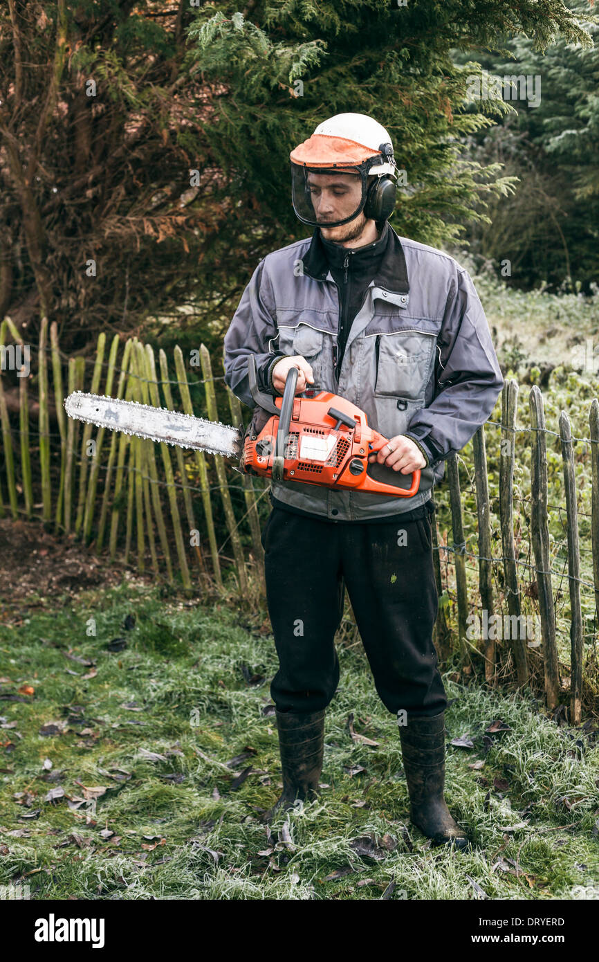 Portrait of professional gardener with chainsaw standing in the garden ...