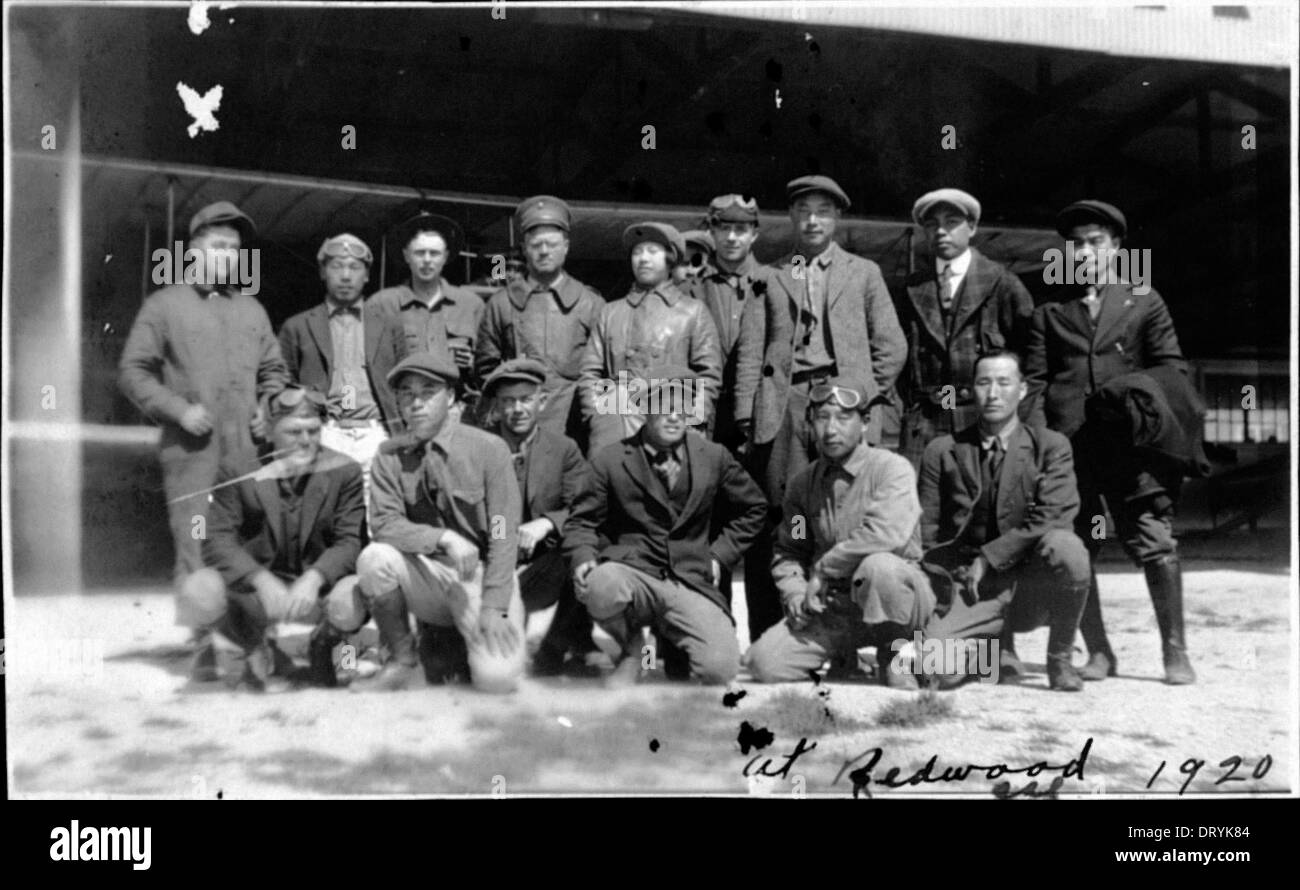 A group of 15 student pilots posing with a plane, likely during a ...