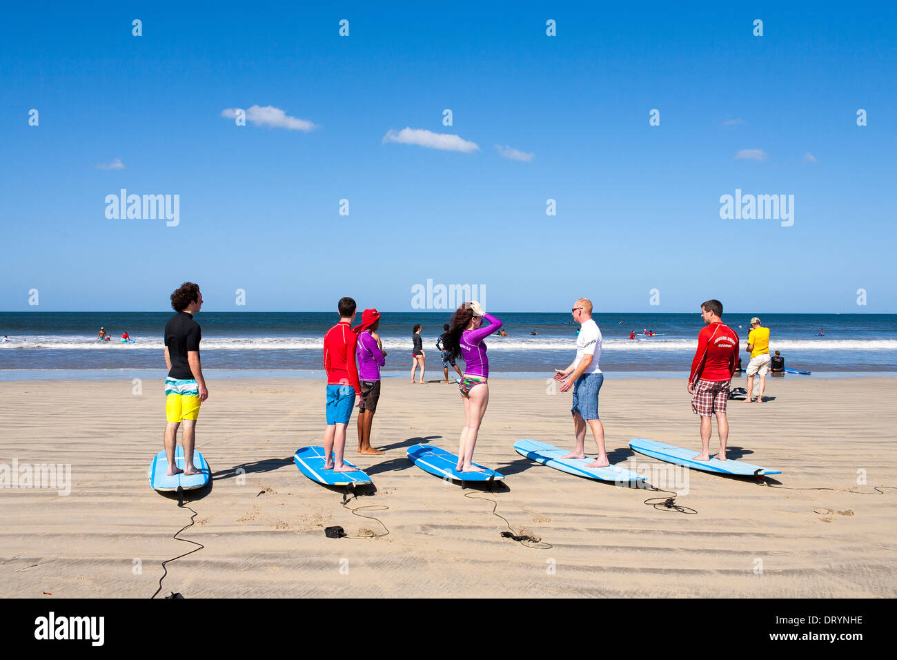 Surfers learn to surf on the beach ready for a surf lesson at a surf ...