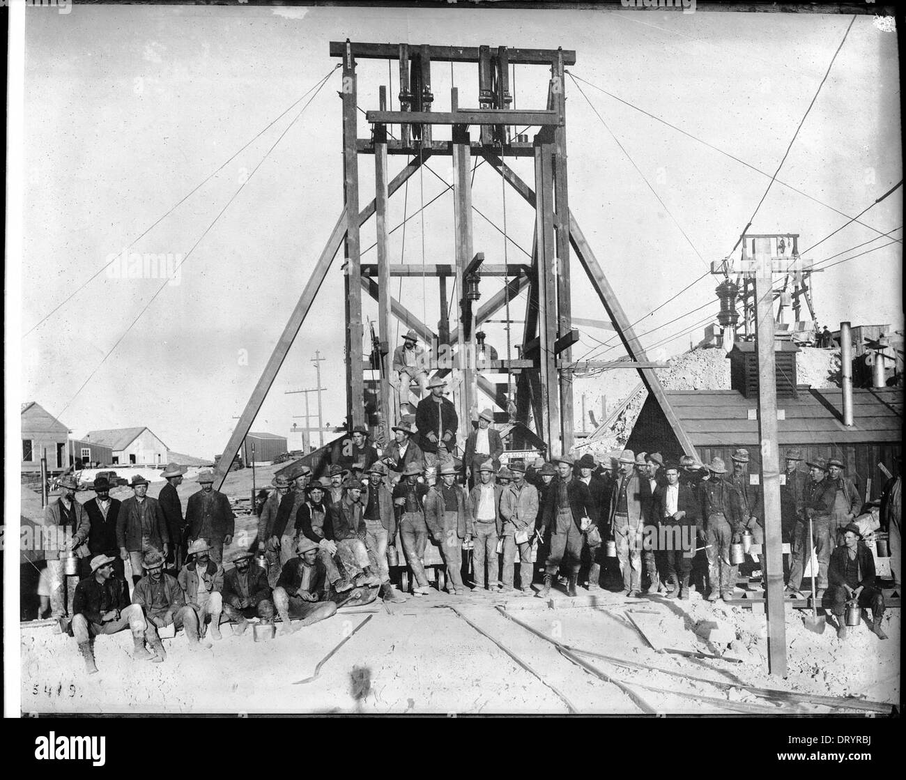 A group of miners (forming a mine shift) pose in front of mine ...