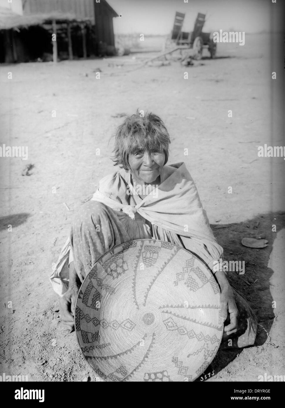 A photograph of an Apache Indian woman weaving a basket, taken around ...
