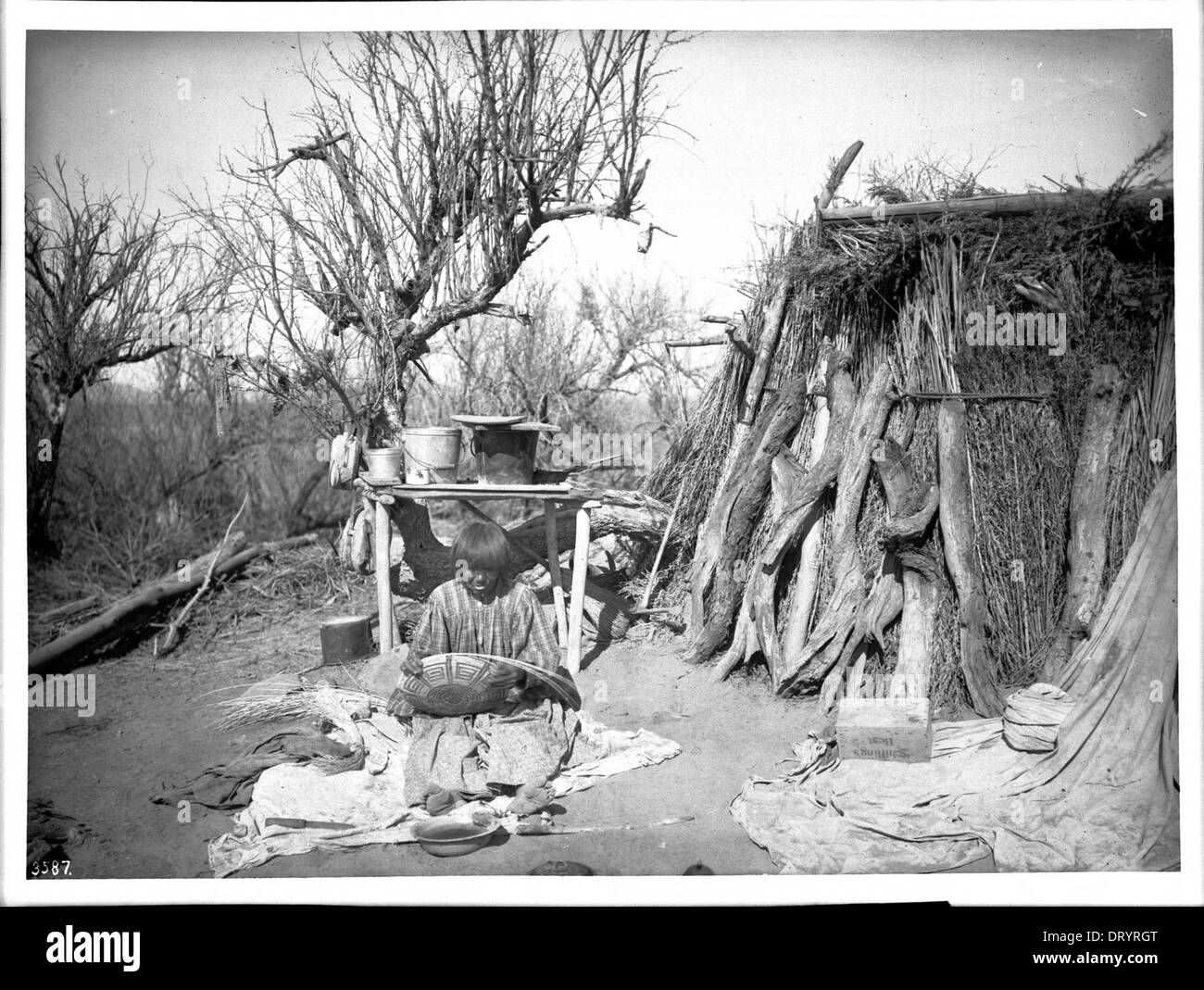 An Apache Indian woman is shown making a basket in front of her ...
