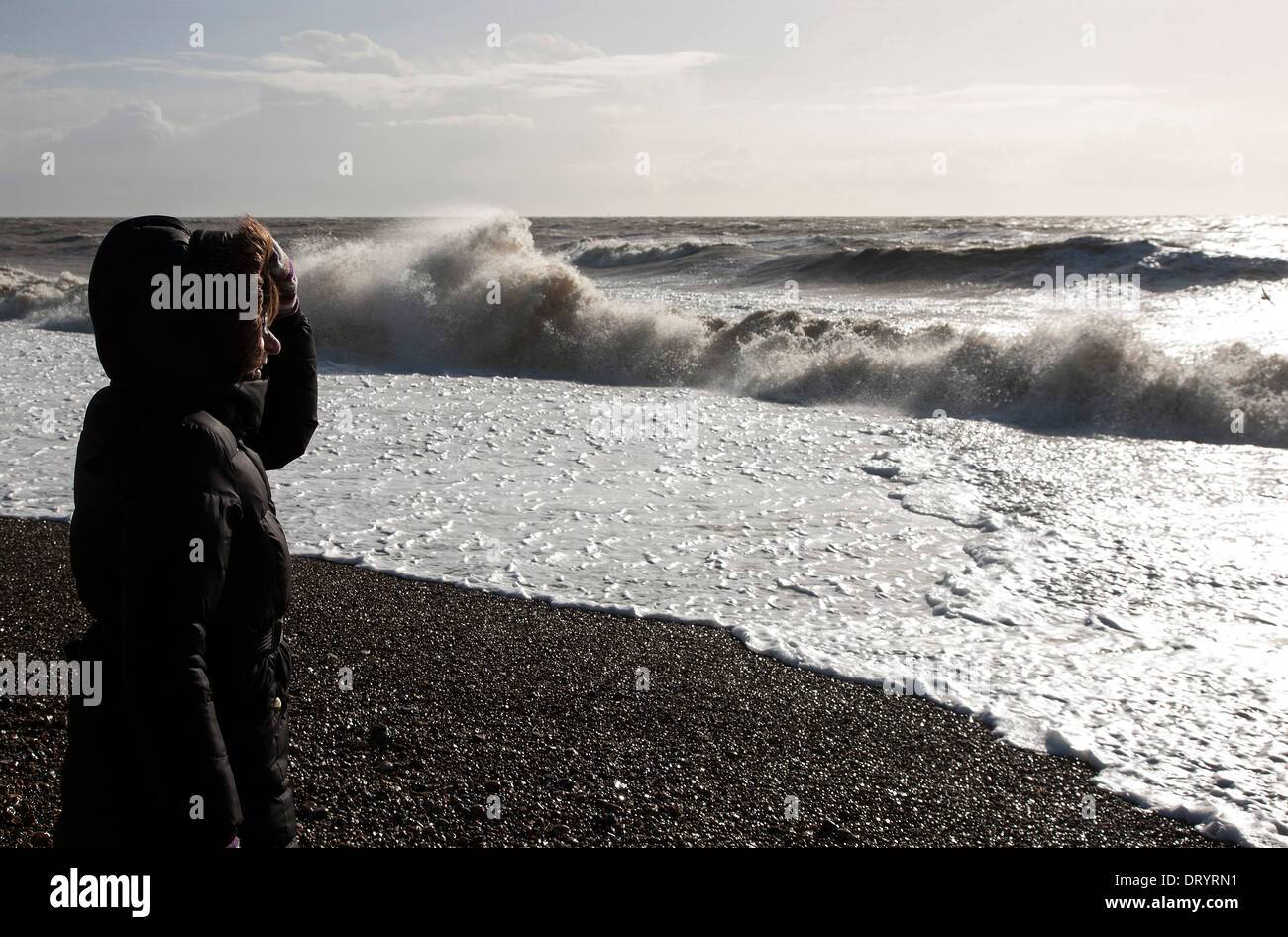 Lady on beach watching high tide storm waves Stock Photo - Alamy