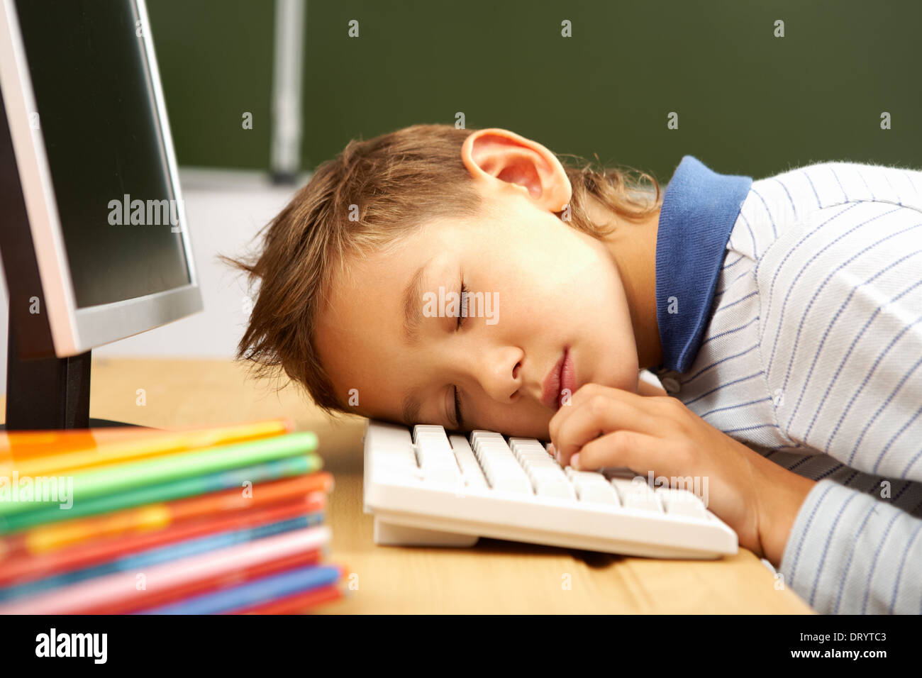 Portrait of cute lad sleeping with his head on computer keyboard in ...