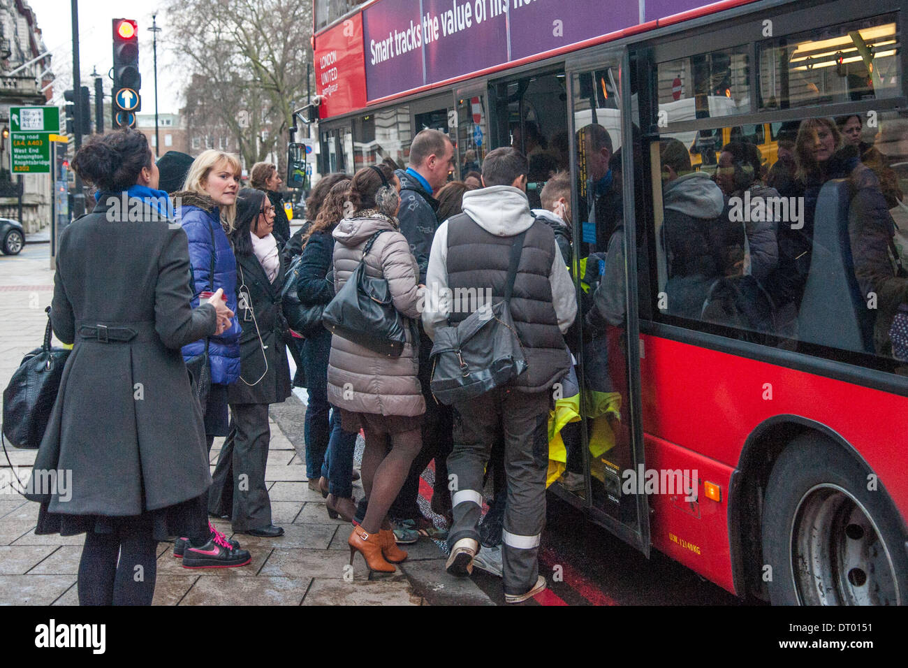 London, UK. Desperate passengers entering a London bus by the exit door ...