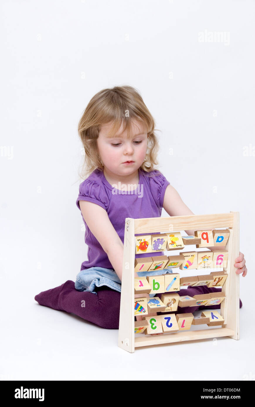 Little Girl learning her alphabet with a wooden spinning letters toy ...