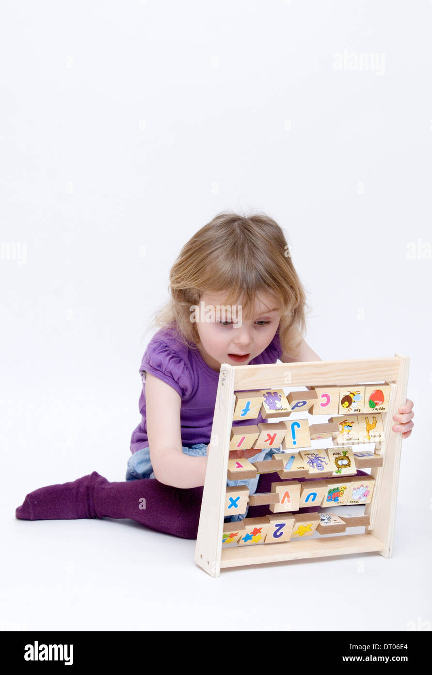 Little Girl learning her alphabet with a wooden spinning letters toy ...