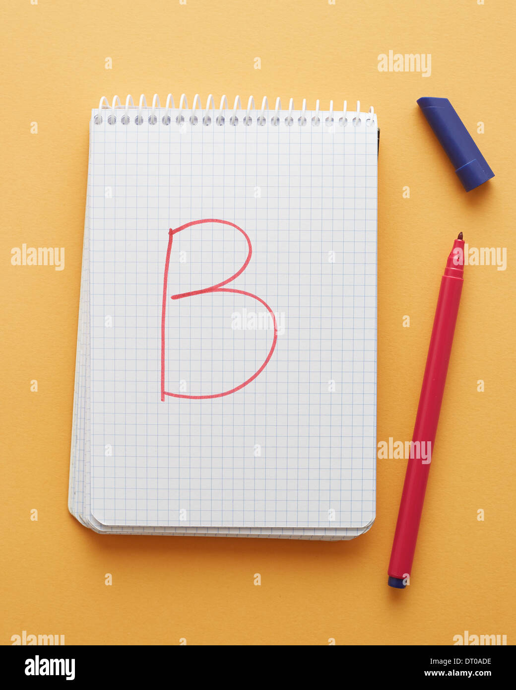 B letter handwritten in notebook page on yellow background alphabet ...