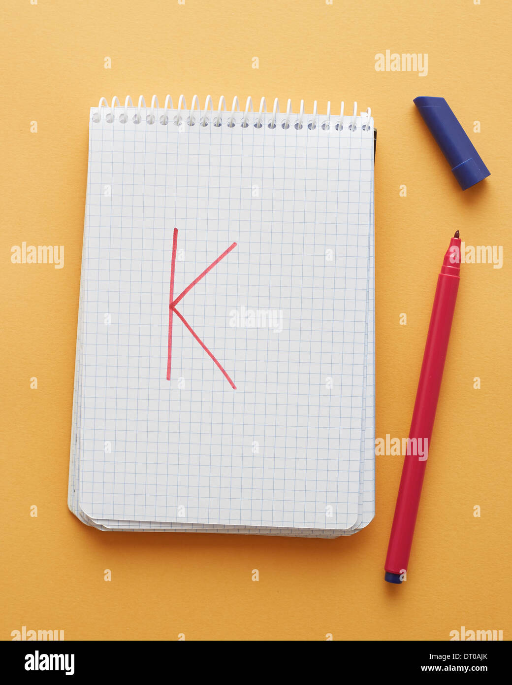 K letter handwritten in notebook page on yellow background alphabet ...