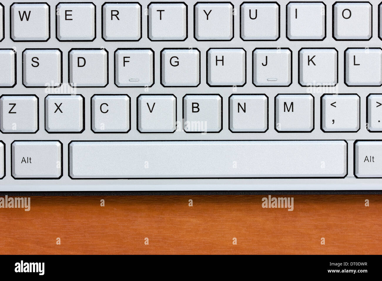 Silver computer keyboard on the wooden desk Stock Photo - Alamy