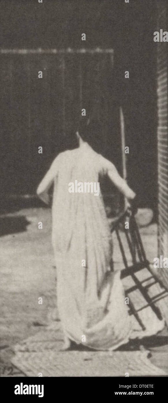 A photograph of a draped woman stepping on a chair, reaching up and ...