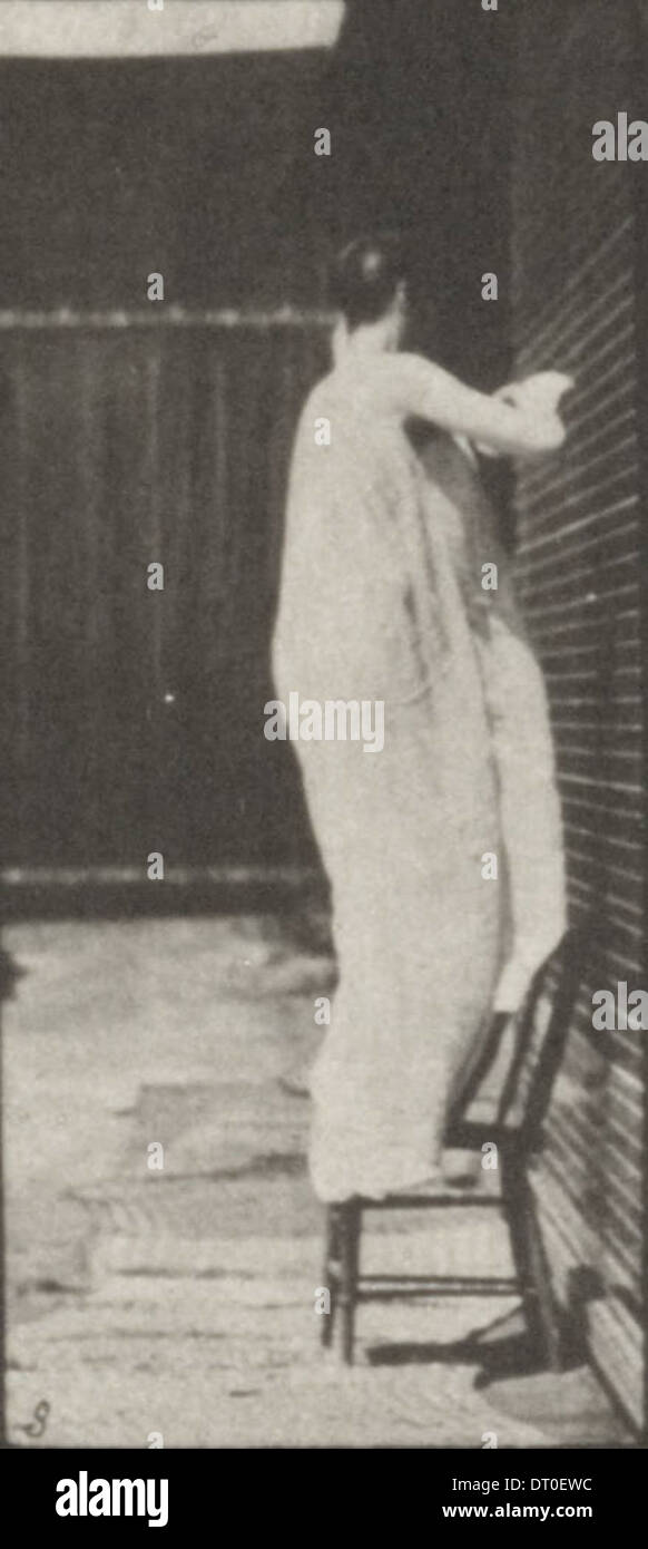 A photograph showing a draped woman stepping on a chair, reaching up ...