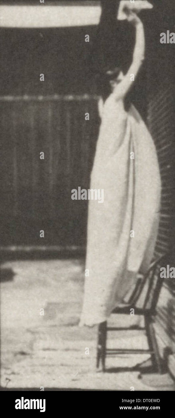 A photograph showing a draped woman stepping on a chair, reaching up ...