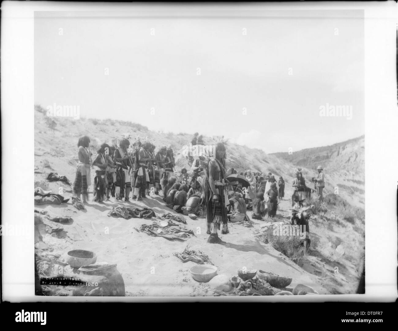 Eight Hopi Indian flute players are seen standing on the side of a hill ...