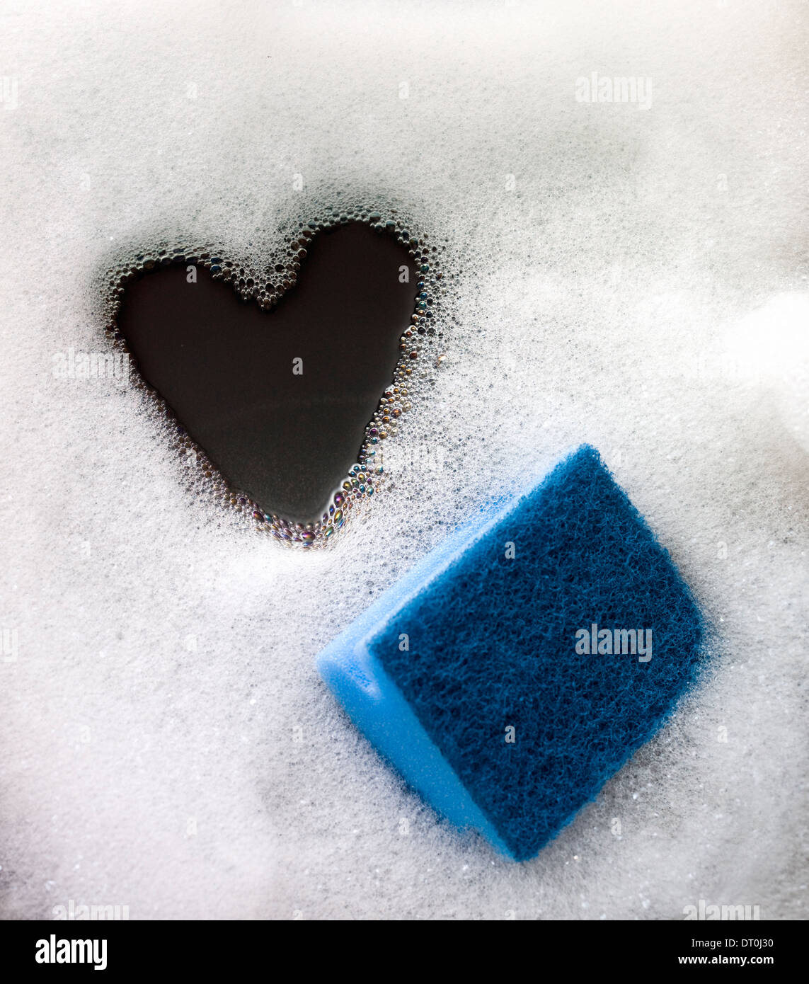 Heart shape in soap suds with blue scourer Stock Photo - Alamy