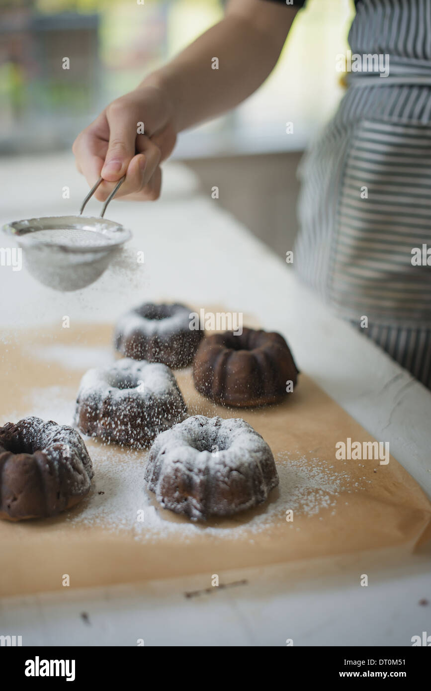 Woodstock New York USA woman dusting fresh chocolate buns icing sugar ...