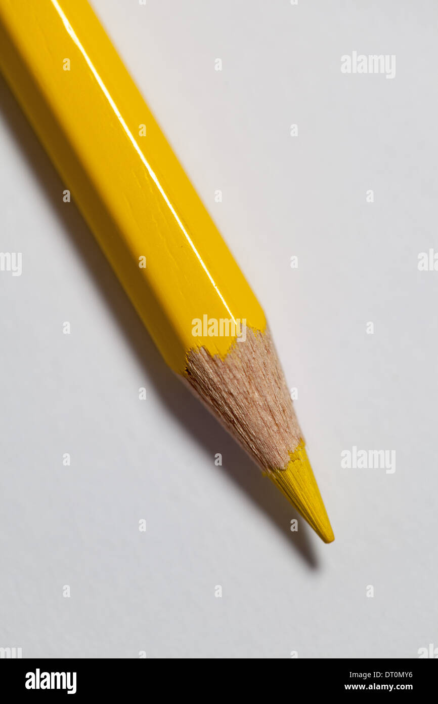 A yellow coloured pencil on a white paper background Stock Photo - Alamy