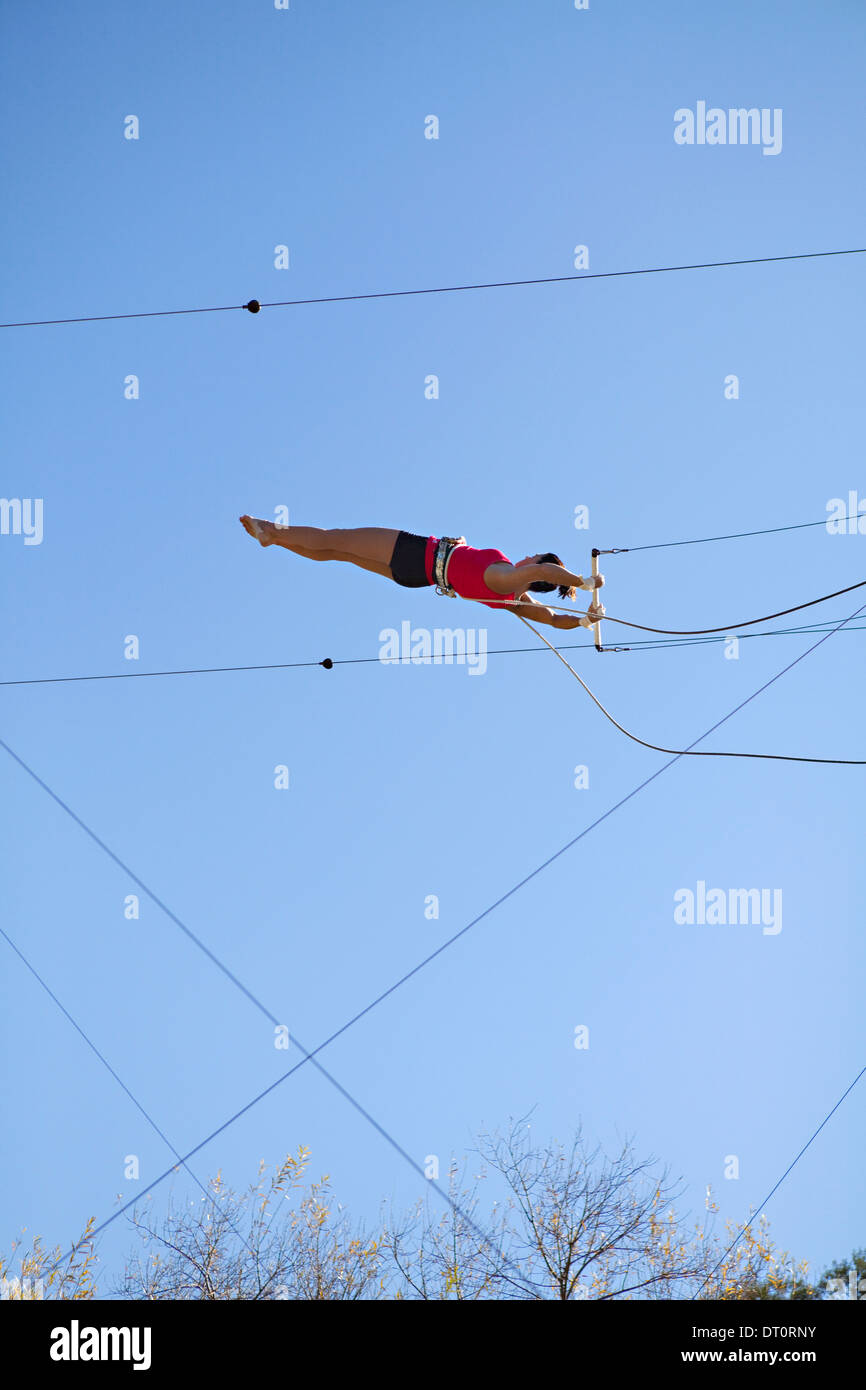 Female acrobat performing on trapez against blue sky Stock Photo - Alamy
