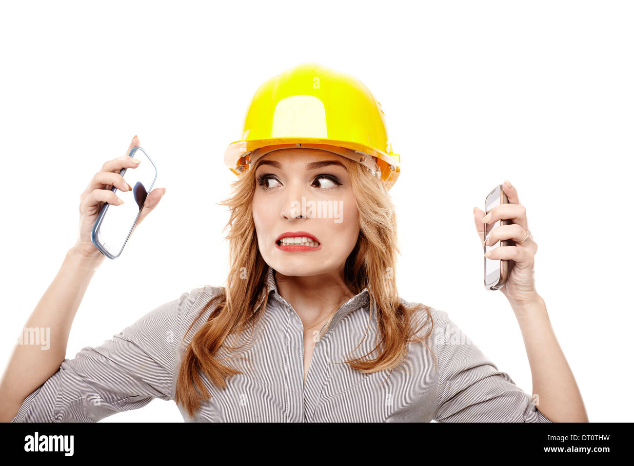 Frustrated woman engineer with protection helmet holding two cell ...