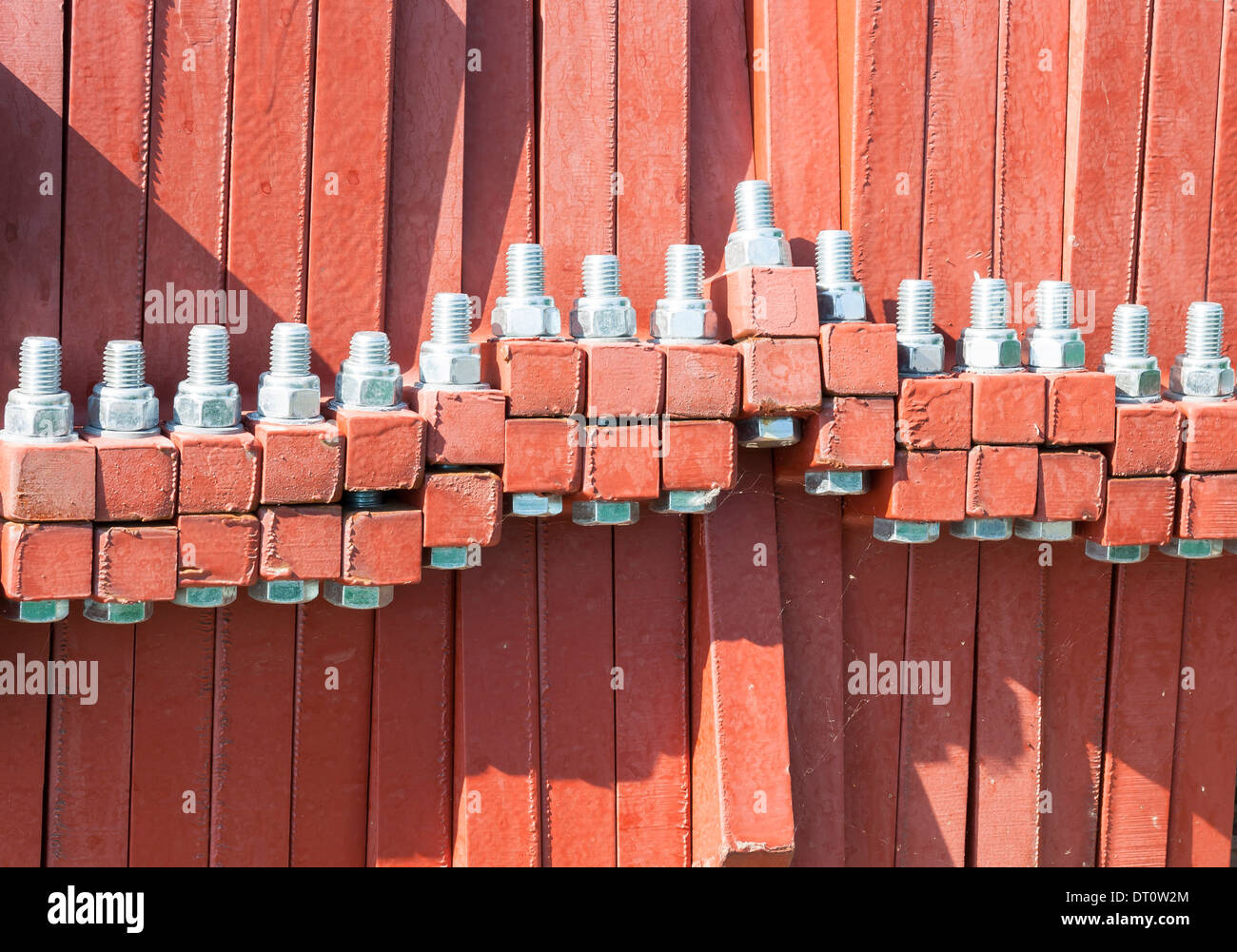 Red objects tied together with bold bolts Stock Photo - Alamy