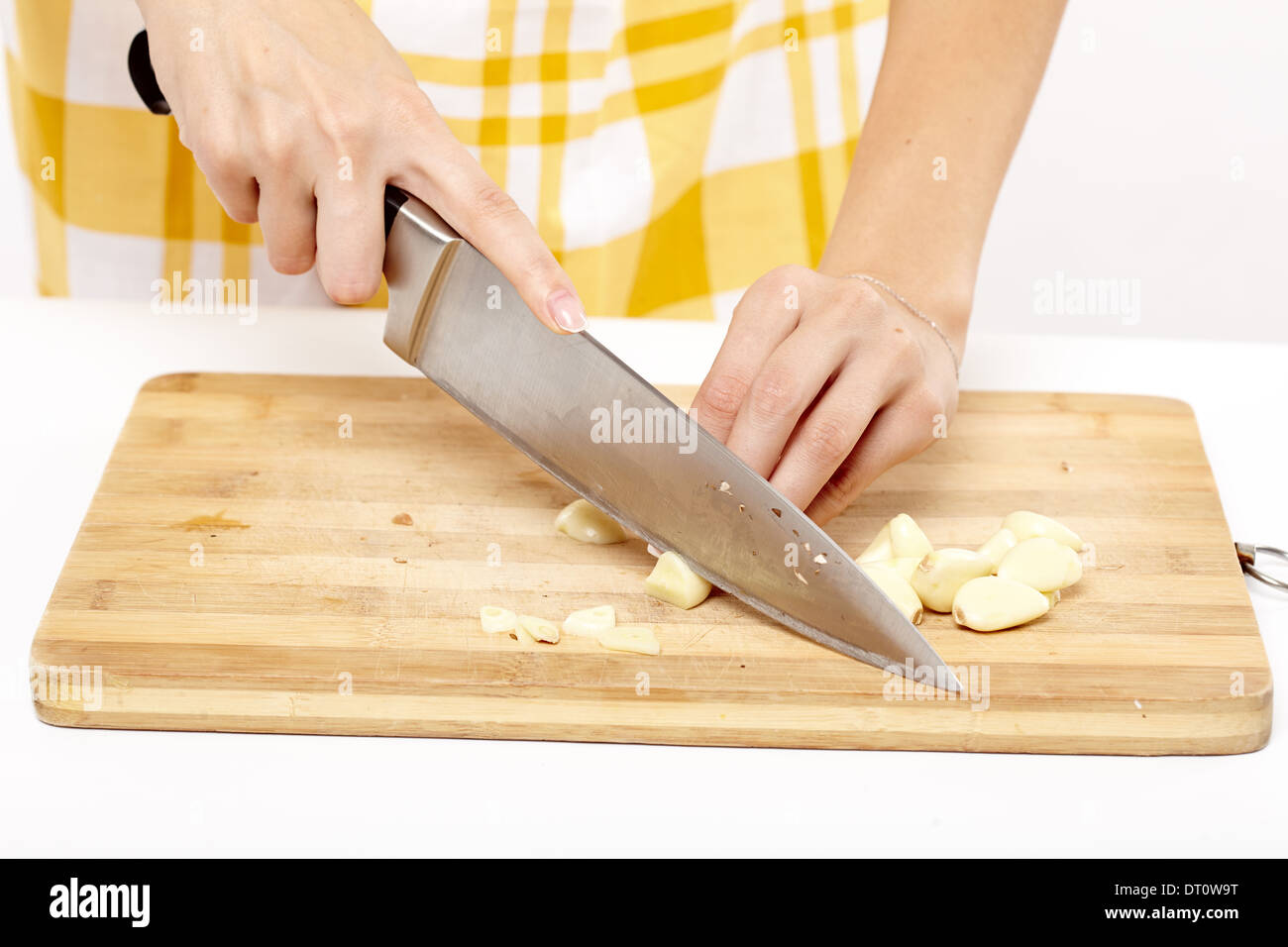 Closeup of cook's hands chopping the garlic on a wooden board, isolated ...