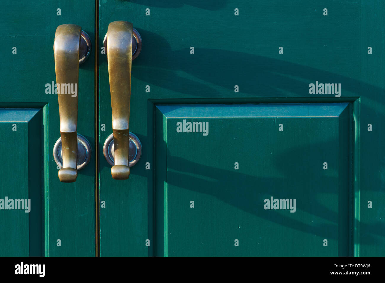 Bronze handles cast shadows on the green door Stock Photo - Alamy