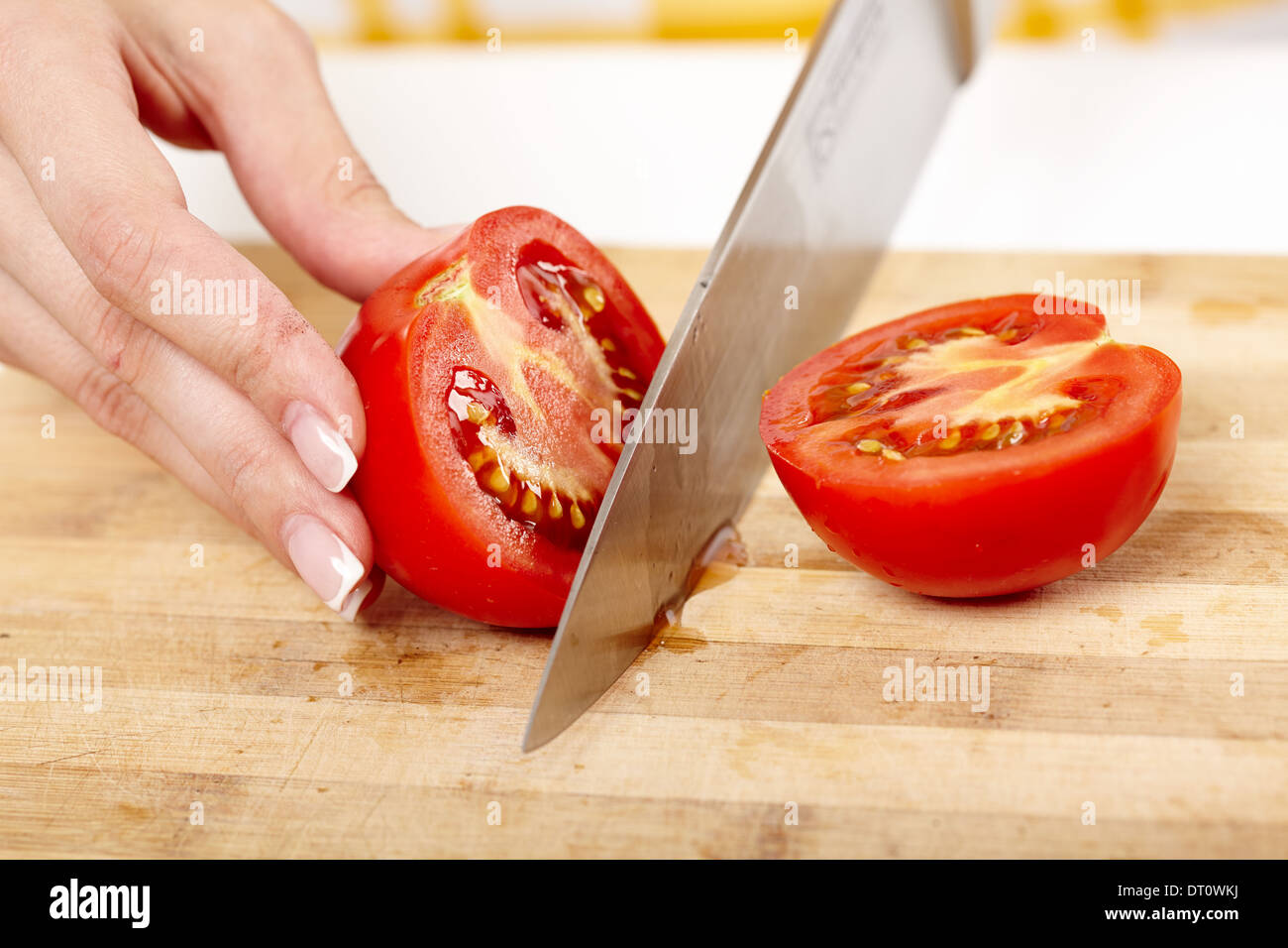 Closeup of woman cook's hand slicing the tomato on a wooden board Stock ...