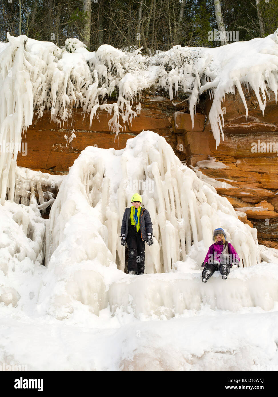 A boy and girl sit on an ice formation at the Apostle Island Ice Caves ...