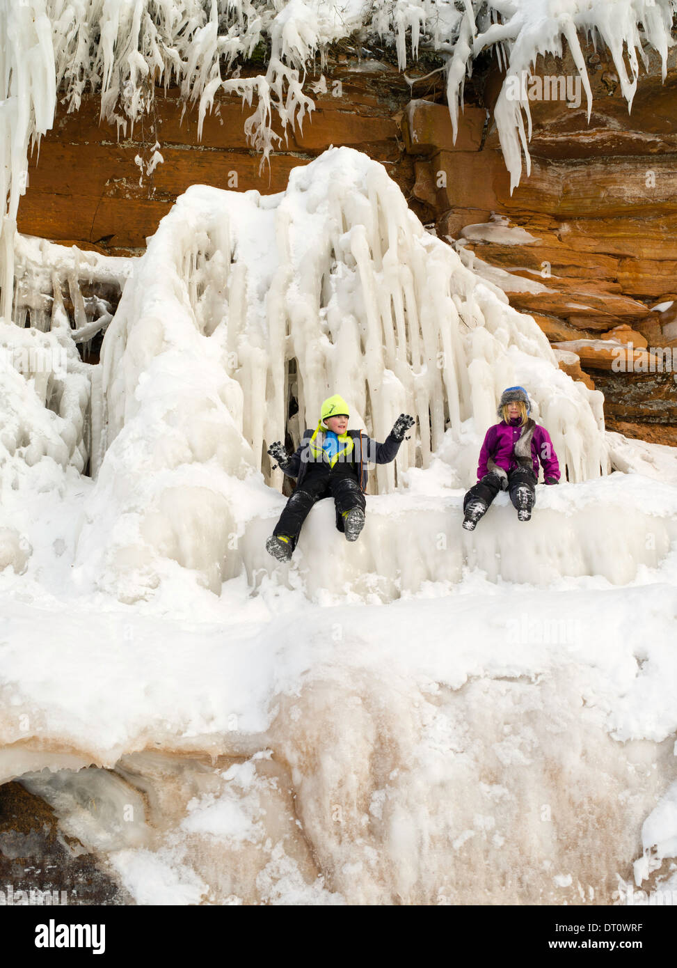 A boy and girl sit on an ice formation at the Apostle Island Ice Caves ...