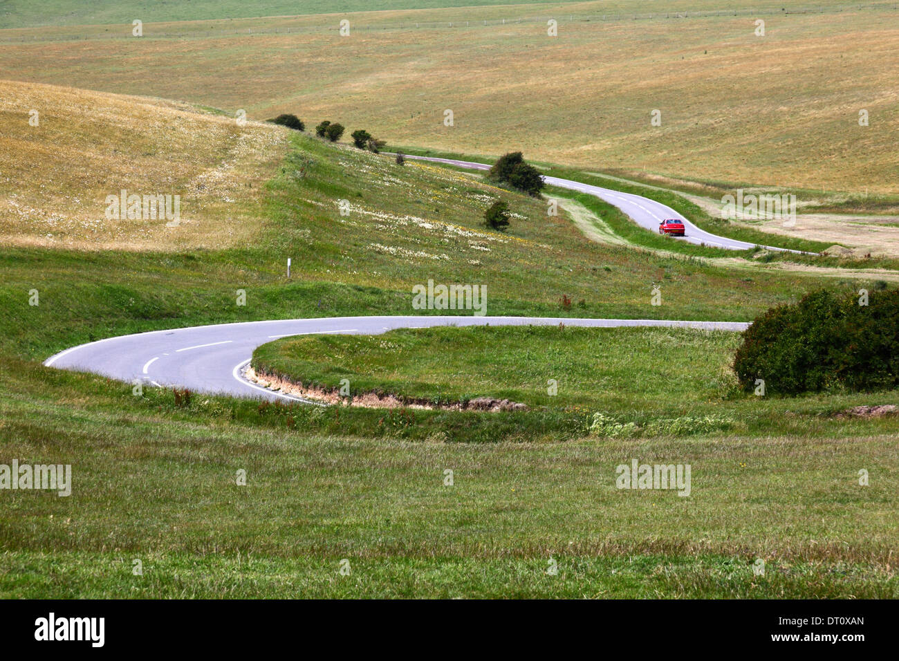 Red car driving along winding road across South Downs near Beachy Head ...