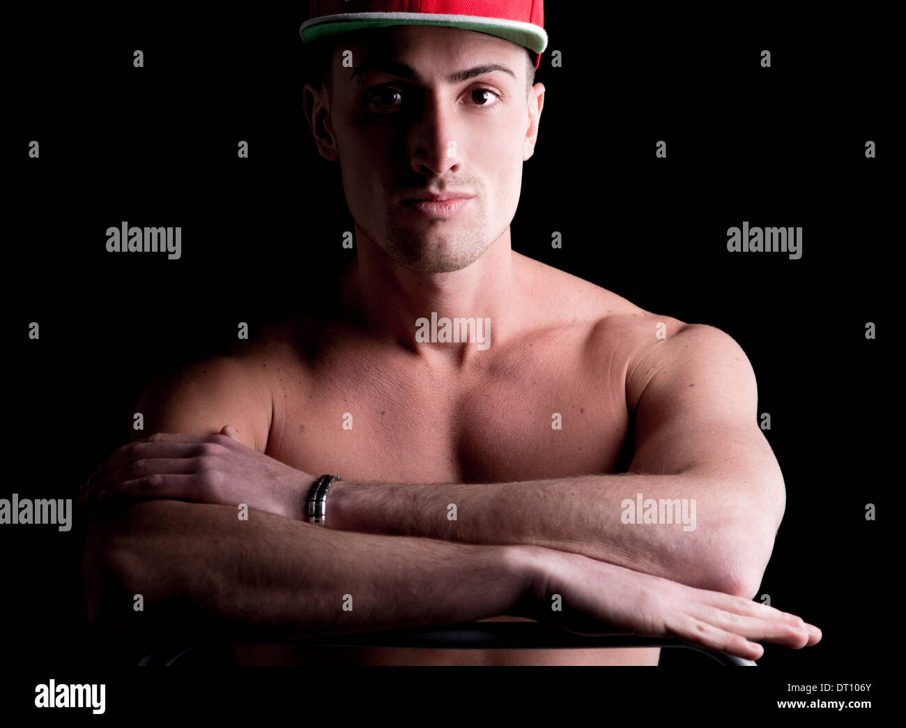 Smiling handsome young man shirtless, arms crossed on bare chest ...