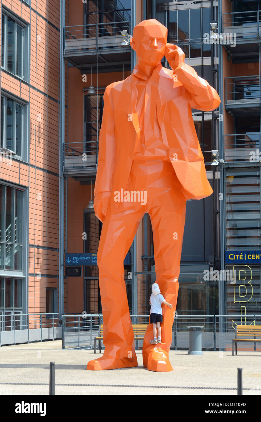 Child climbing giant orange statue of man on mobile phone L ...