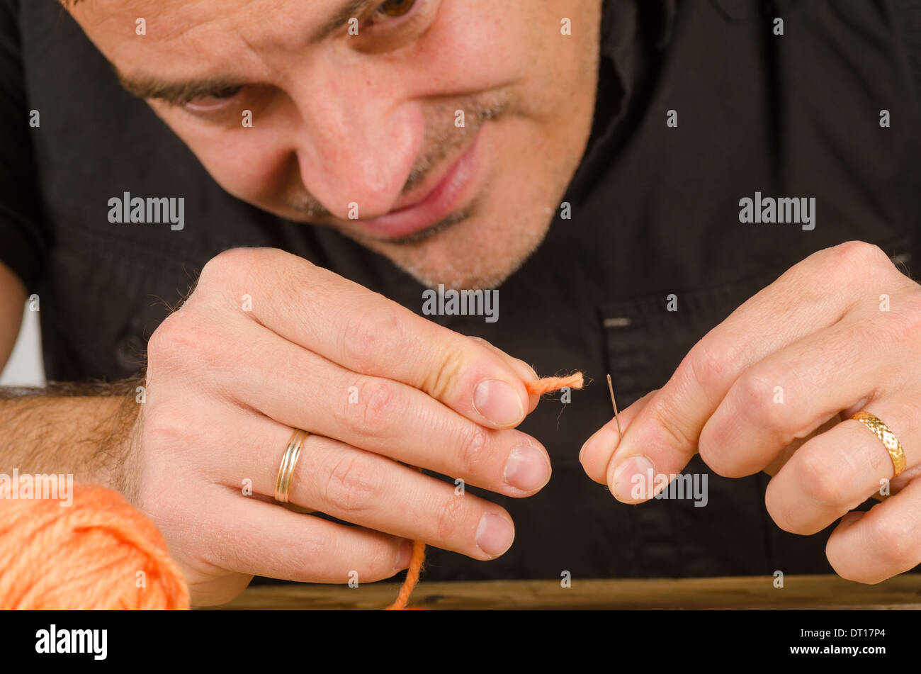 Guy having a hard time with needle and thread Stock Photo - Alamy