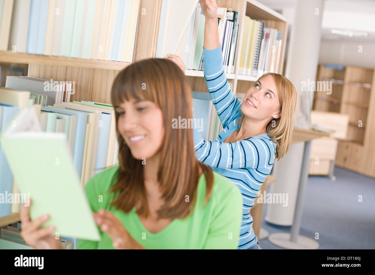 Student in library - two woman choose book Stock Photo - Alamy