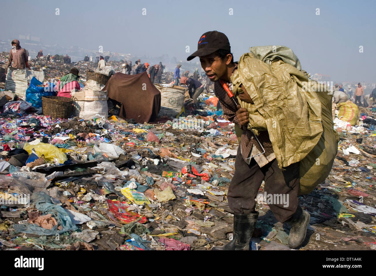 A scavenger man is carrying a sack while collecting recyclable Stock ...