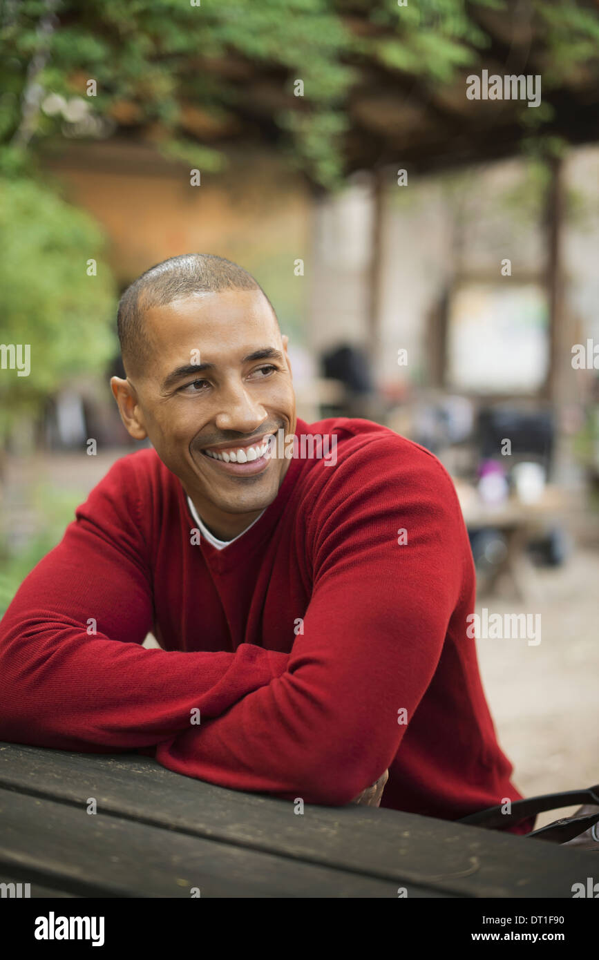 Scenes from urban life in New York City A man in a red jumper seated at ...