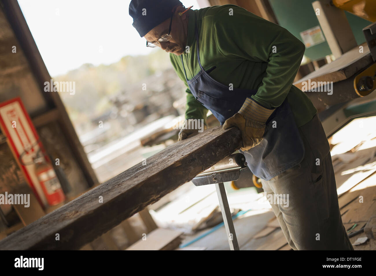 A man examining a large plank of cut wood in a reclaimed timber yard A ...