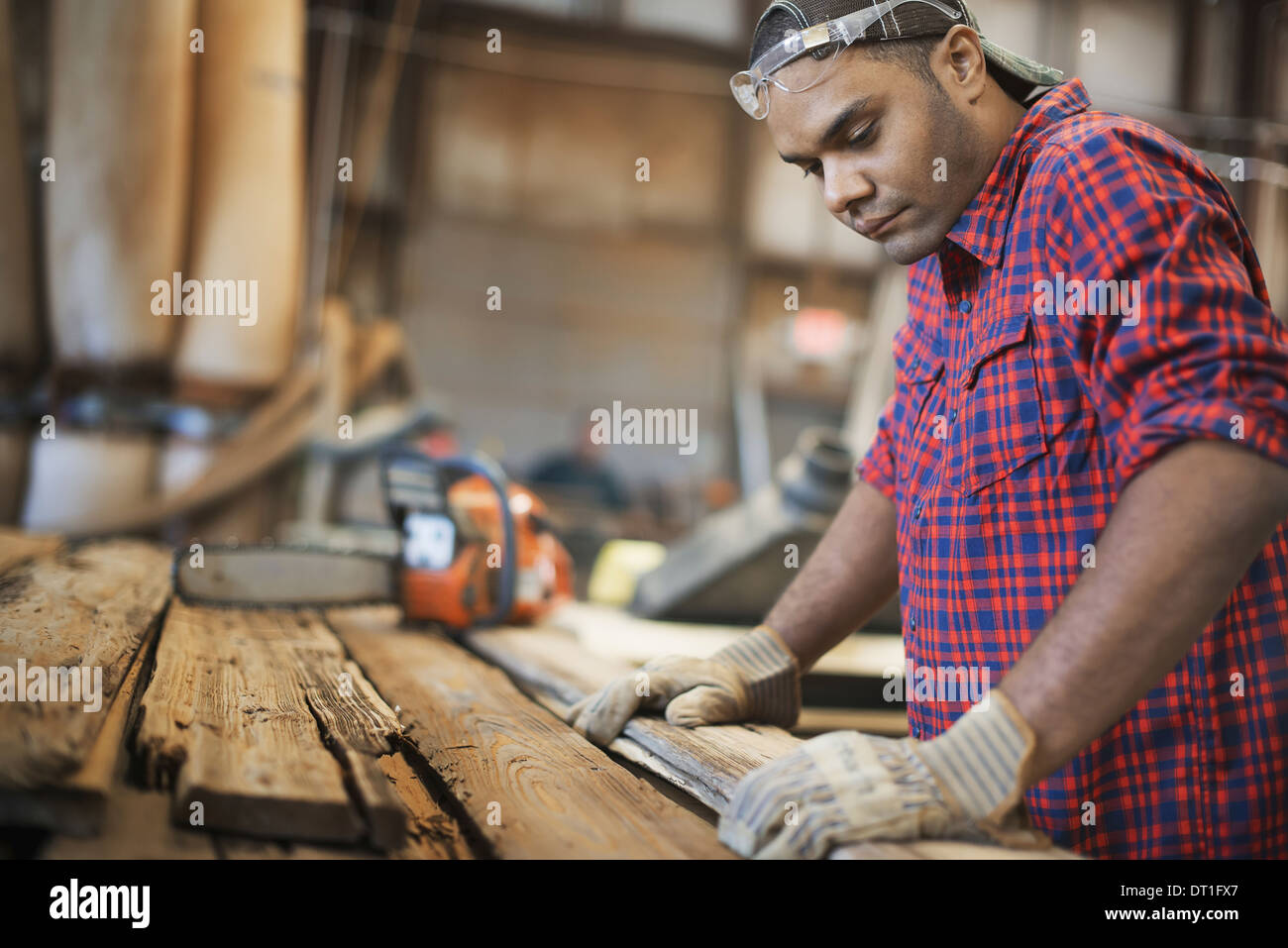 A reclaimed lumber workshop A man measuring and checking planks of wood ...