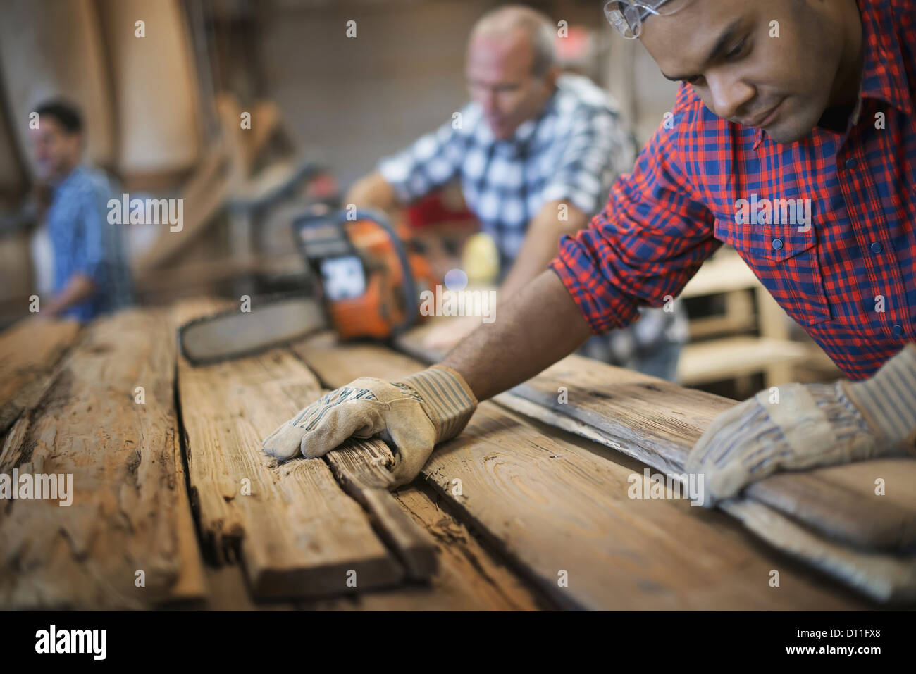 A reclaimed lumber workshop A group of people working A man measuring ...