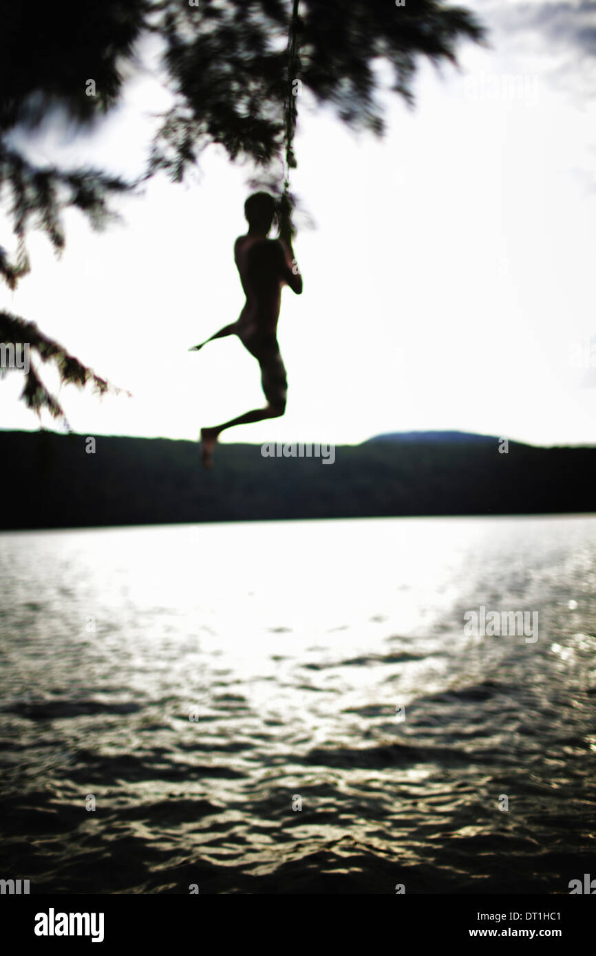 Boy jumping off rope swing Stock Photo - Alamy