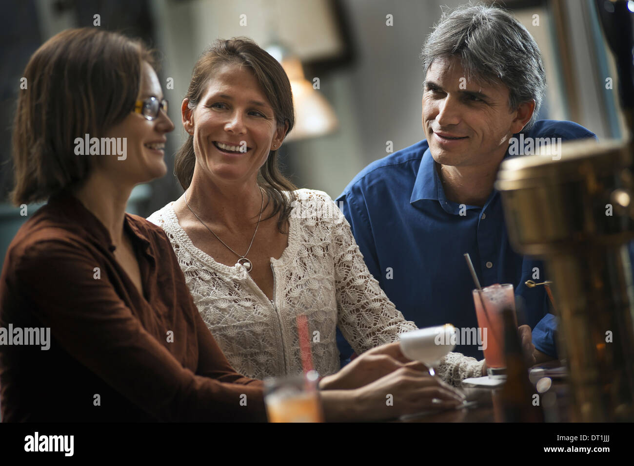 Three people meeting for a drink Two women and a man sitting at a bar ...