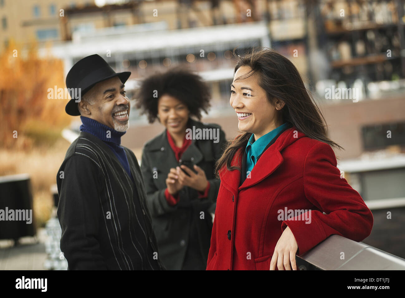 using mobile phones and talking to each other Two women and a man Stock ...