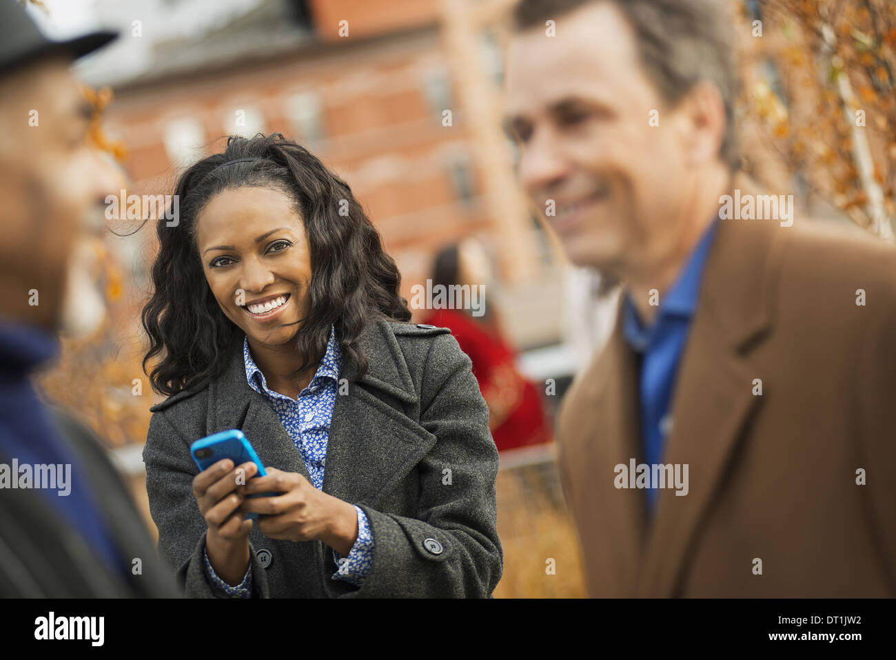 using mobile phones and talking to each other Two men and a woman Stock ...