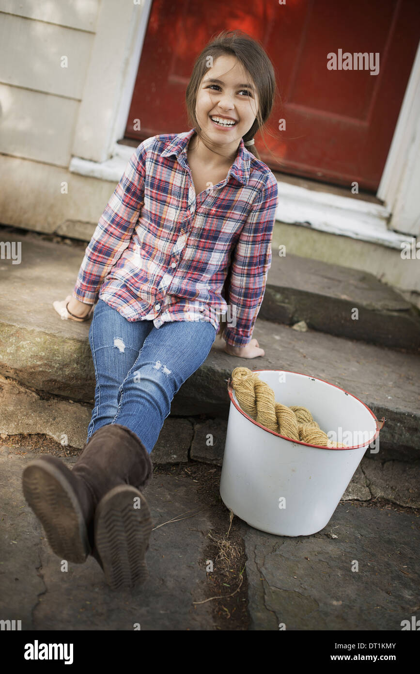 A girl sitting on a step with a large iron pail and gloves Stock Photo ...